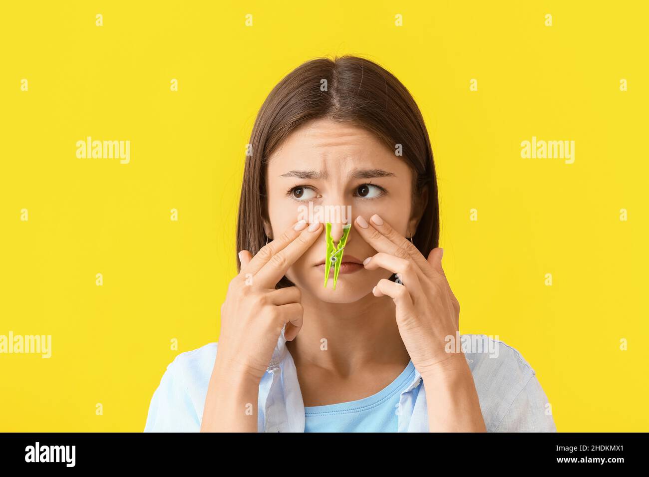 Ill young woman with clothespin on her nose against color background ...