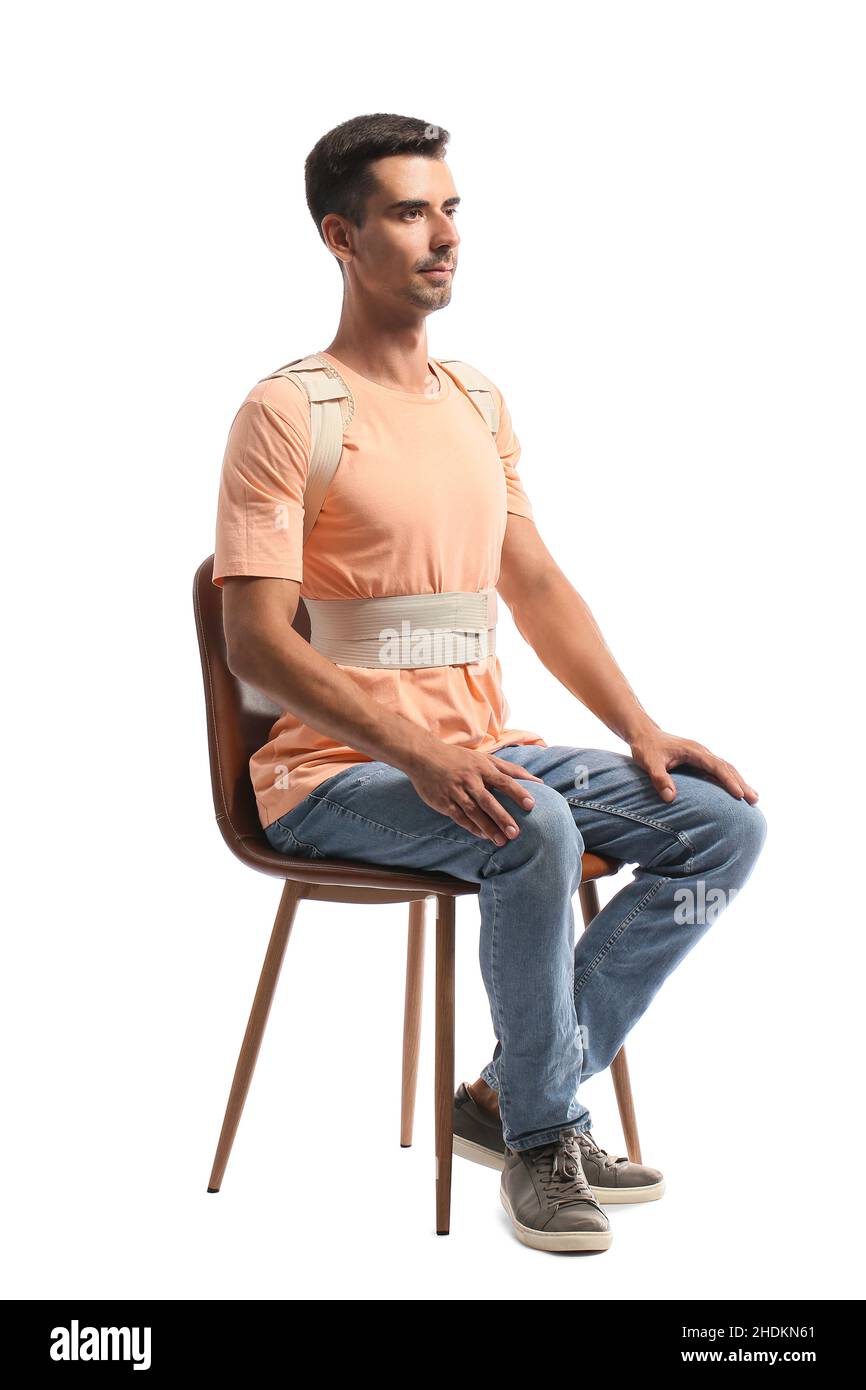 Young man in back brace sitting on chair against white background Stock ...