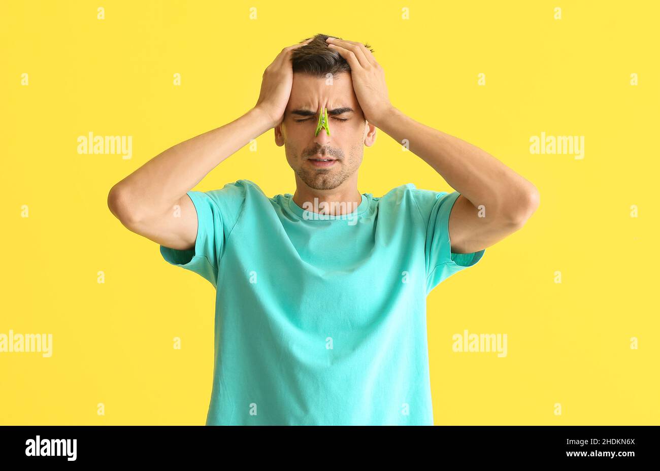 Ill young man with clothespin on his nose against color background ...