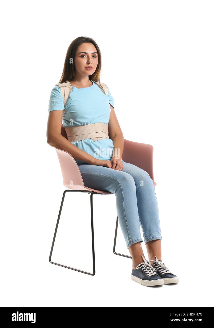 Young woman in back brace sitting on chair against white background ...
