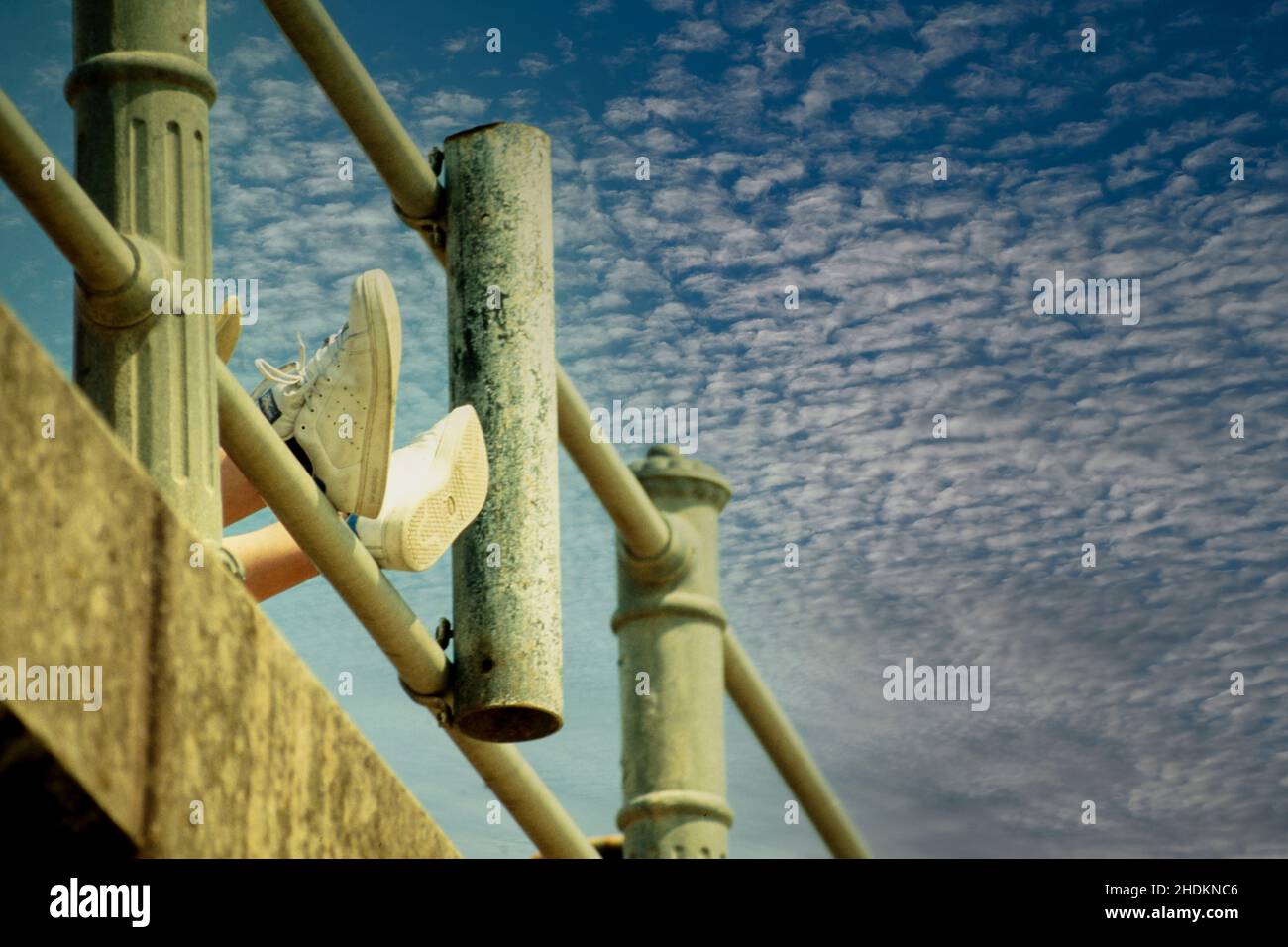 Feet resting on diagonal railings with summer sky. Abstract still life ...