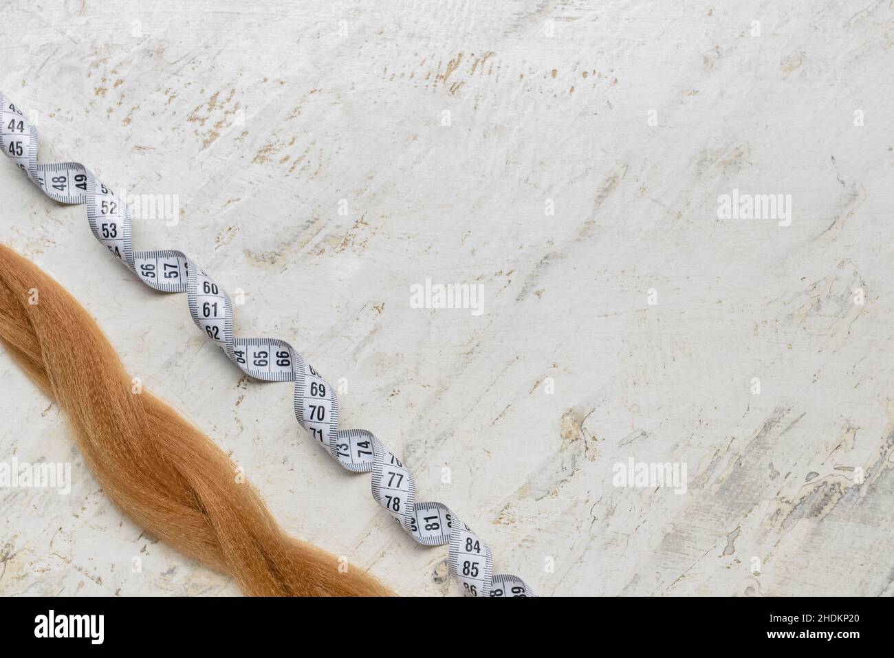 Red hair strand for donation with measuring tape on grunge background ...
