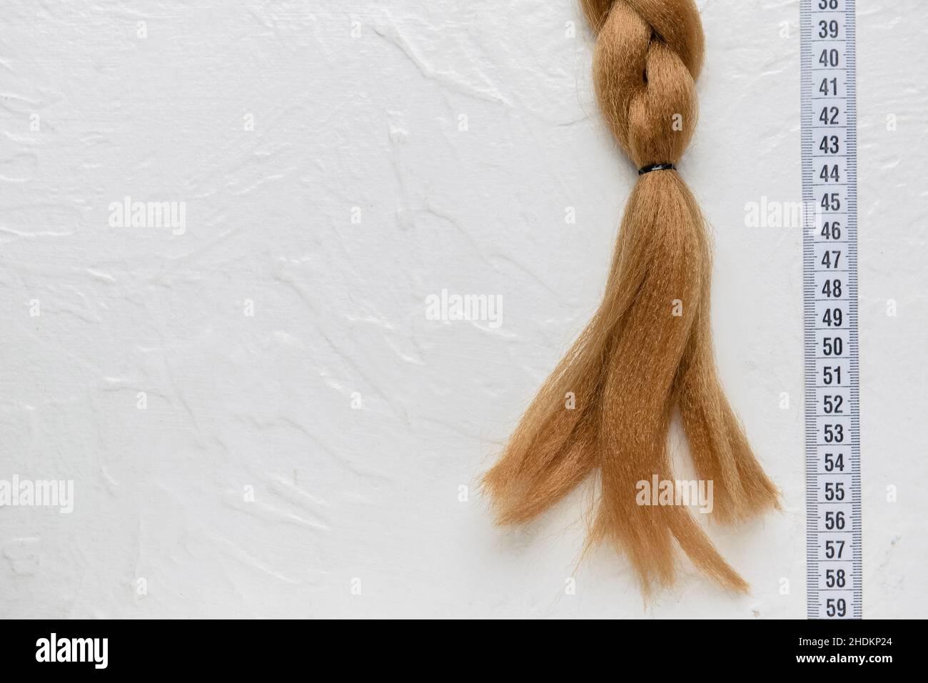 Braided red hair for donation with measuring tape on white background ...