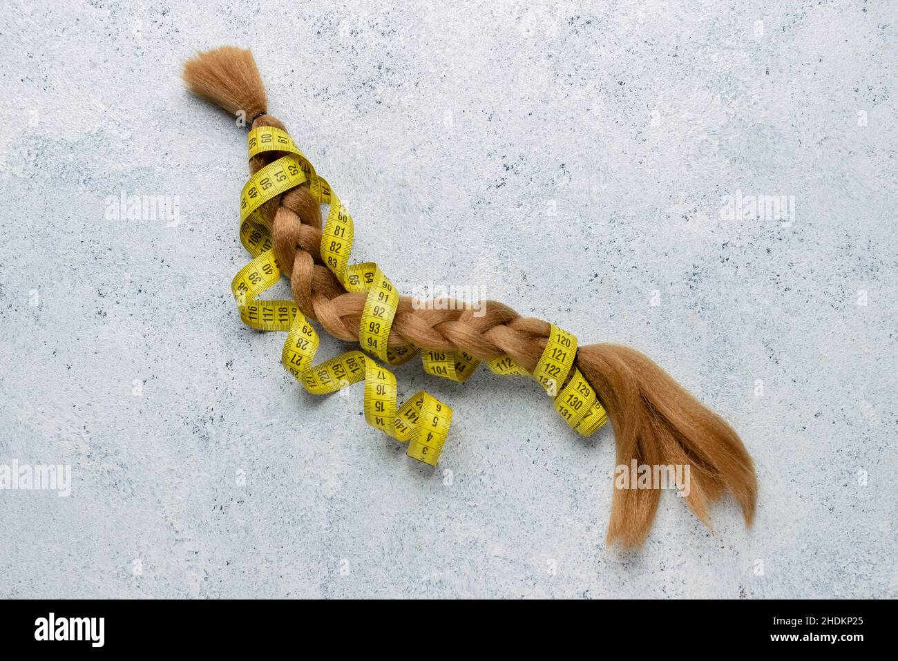 Braided red hair for donation with measuring tape on grunge background ...