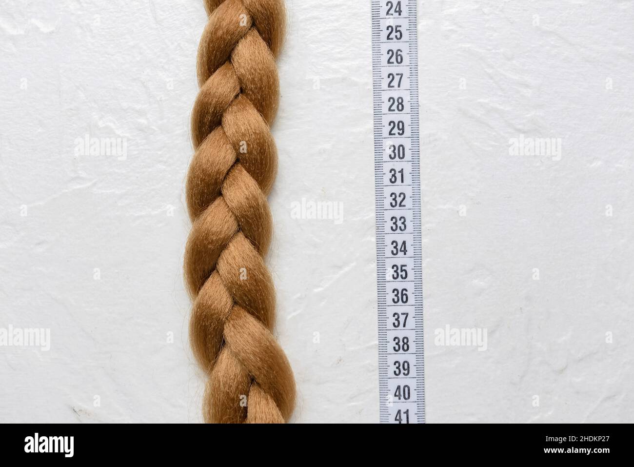 Braided red hair for donation with measuring tape on white background ...