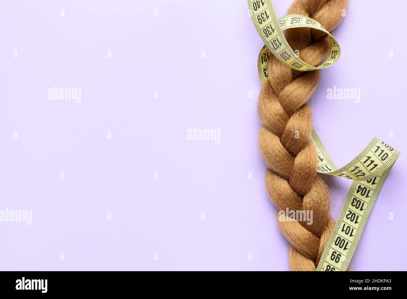 Braided red hair for donation with measuring tape on lilac background ...