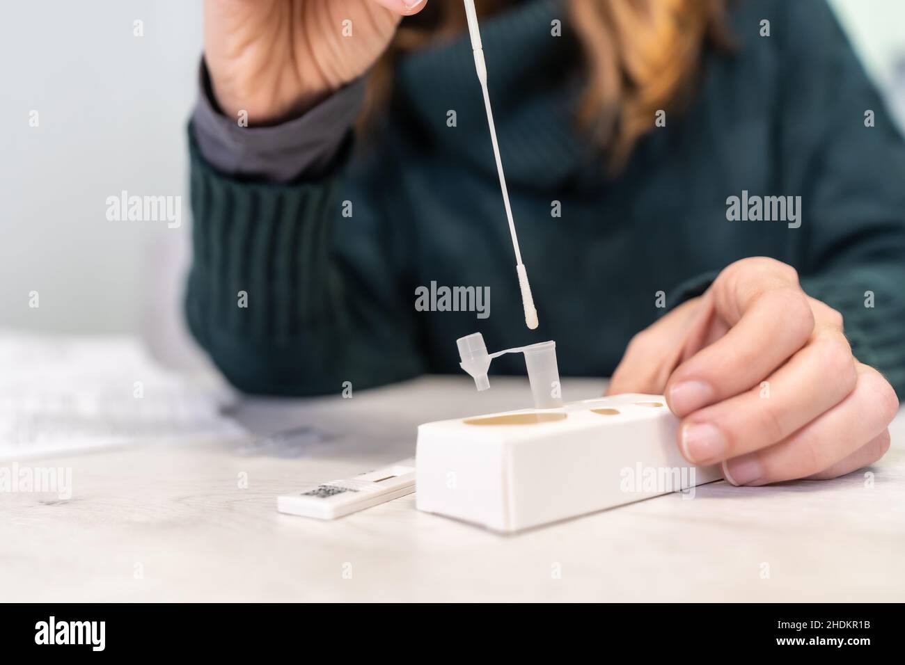 Putting the swab in the reagent liquid. A young woman doing the rapid ...