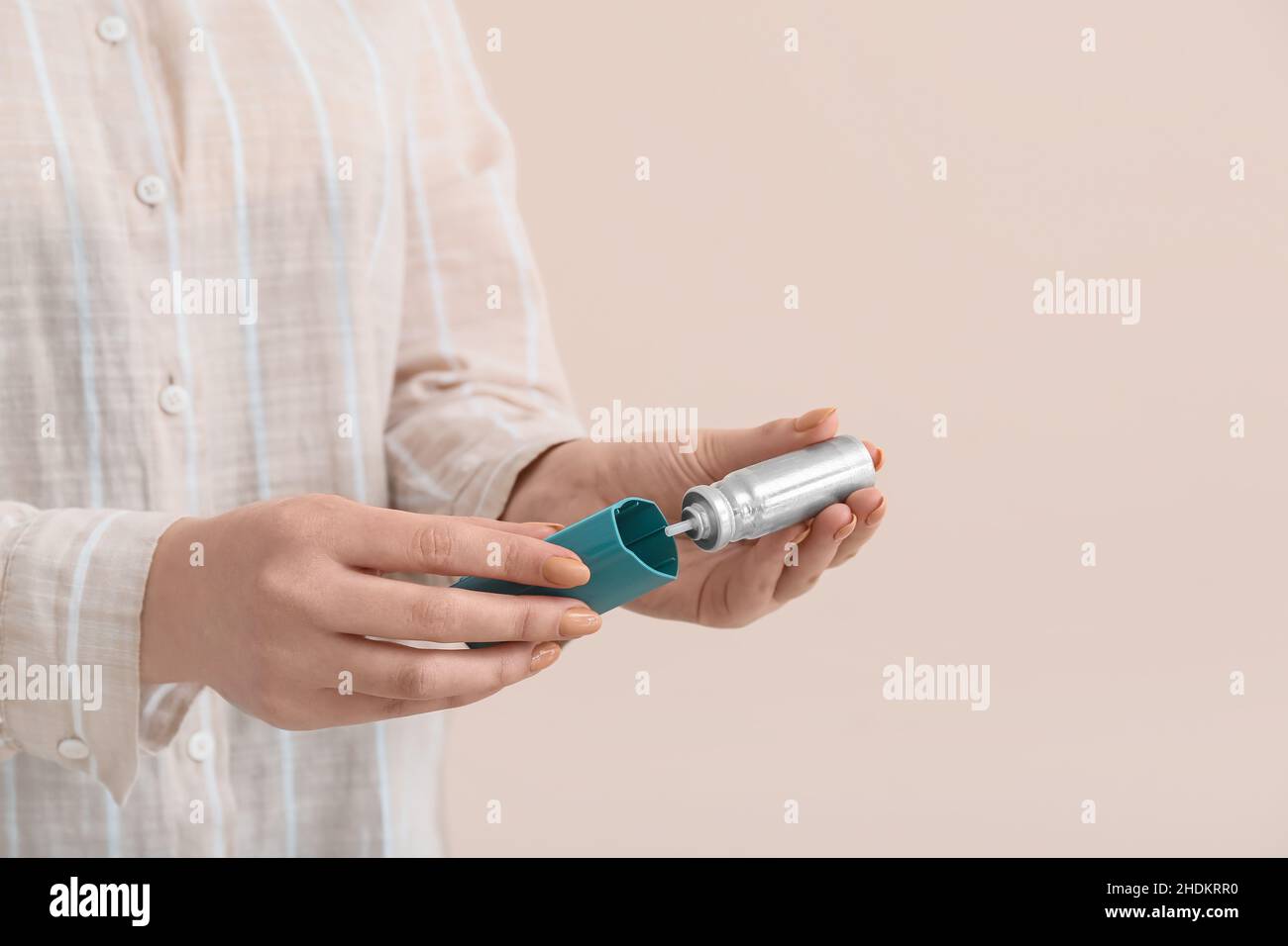 Woman holding asthma inhaler on beige background Stock Photo - Alamy