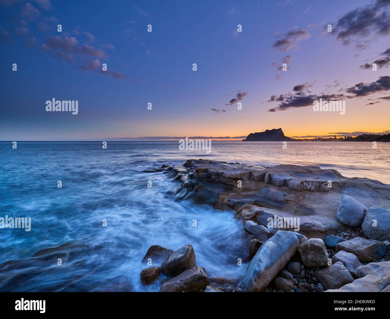 Scenic view of rocks coming out of water under a sunset-colored sky in ...