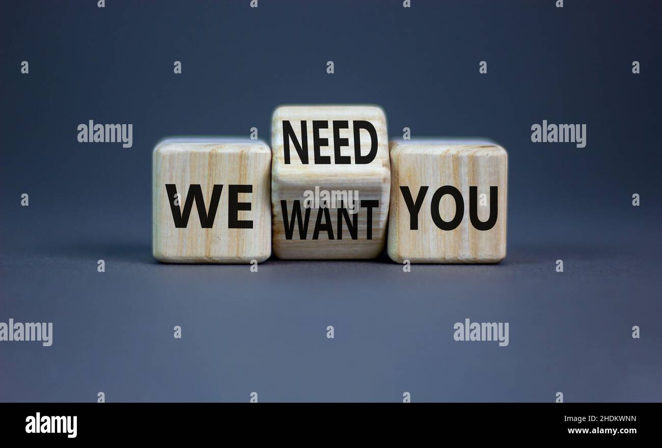We want and need you symbol. Businessman turns the wooden cube and ...