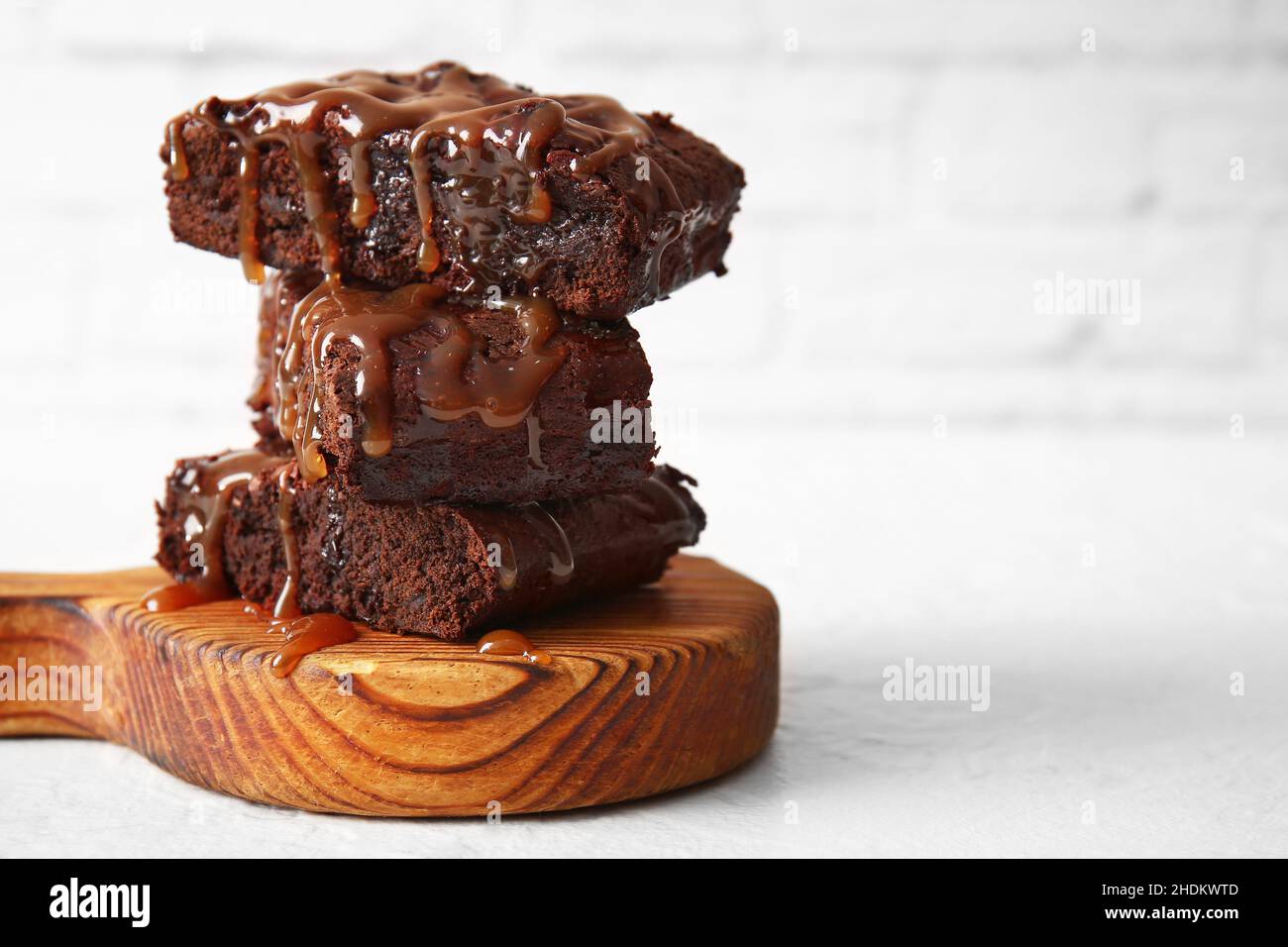 Wooden board with pieces of tasty chocolate brownie on table Stock ...