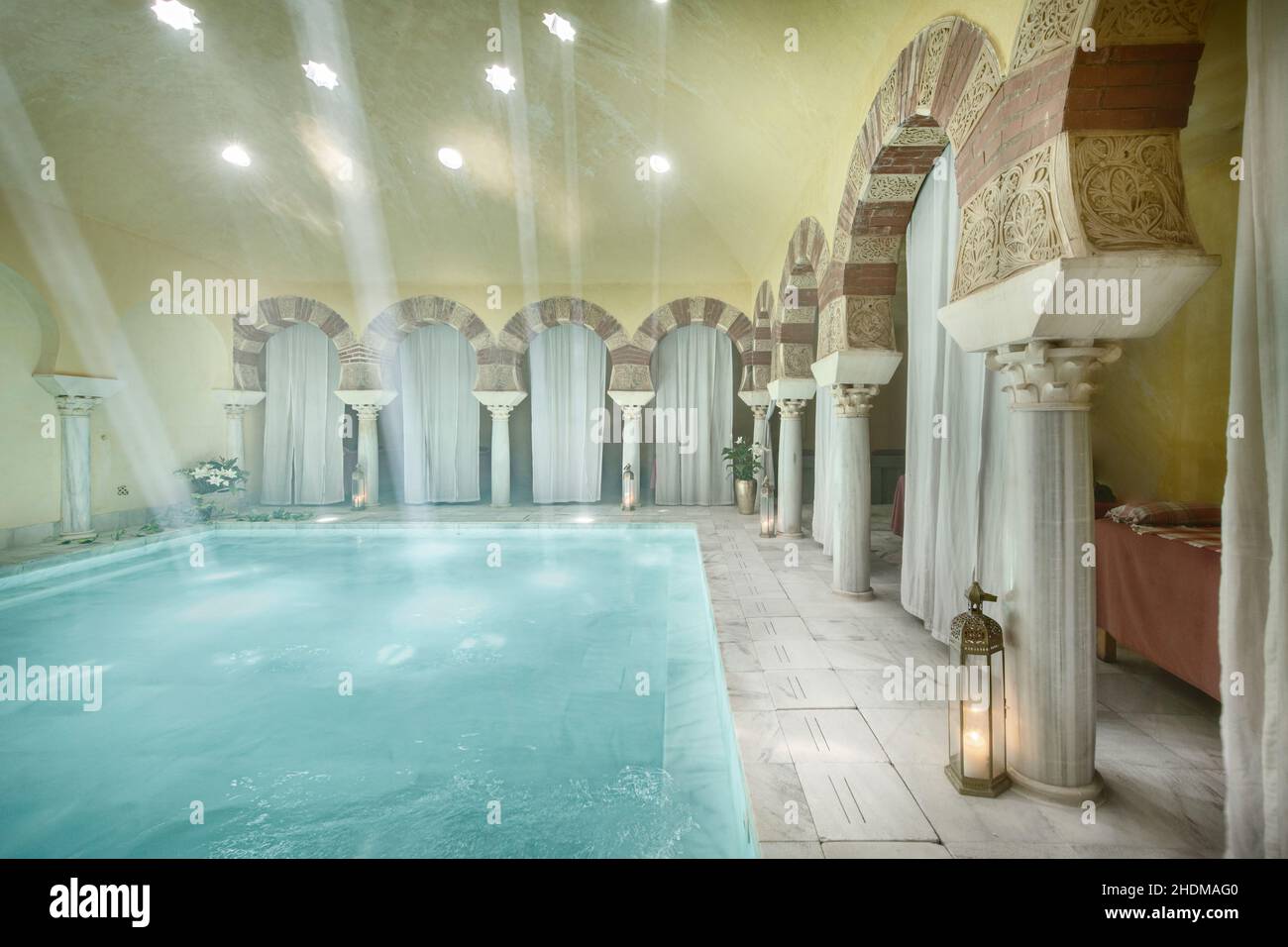 Thermal water pool with rays of light falling on the surface surrounded ...
