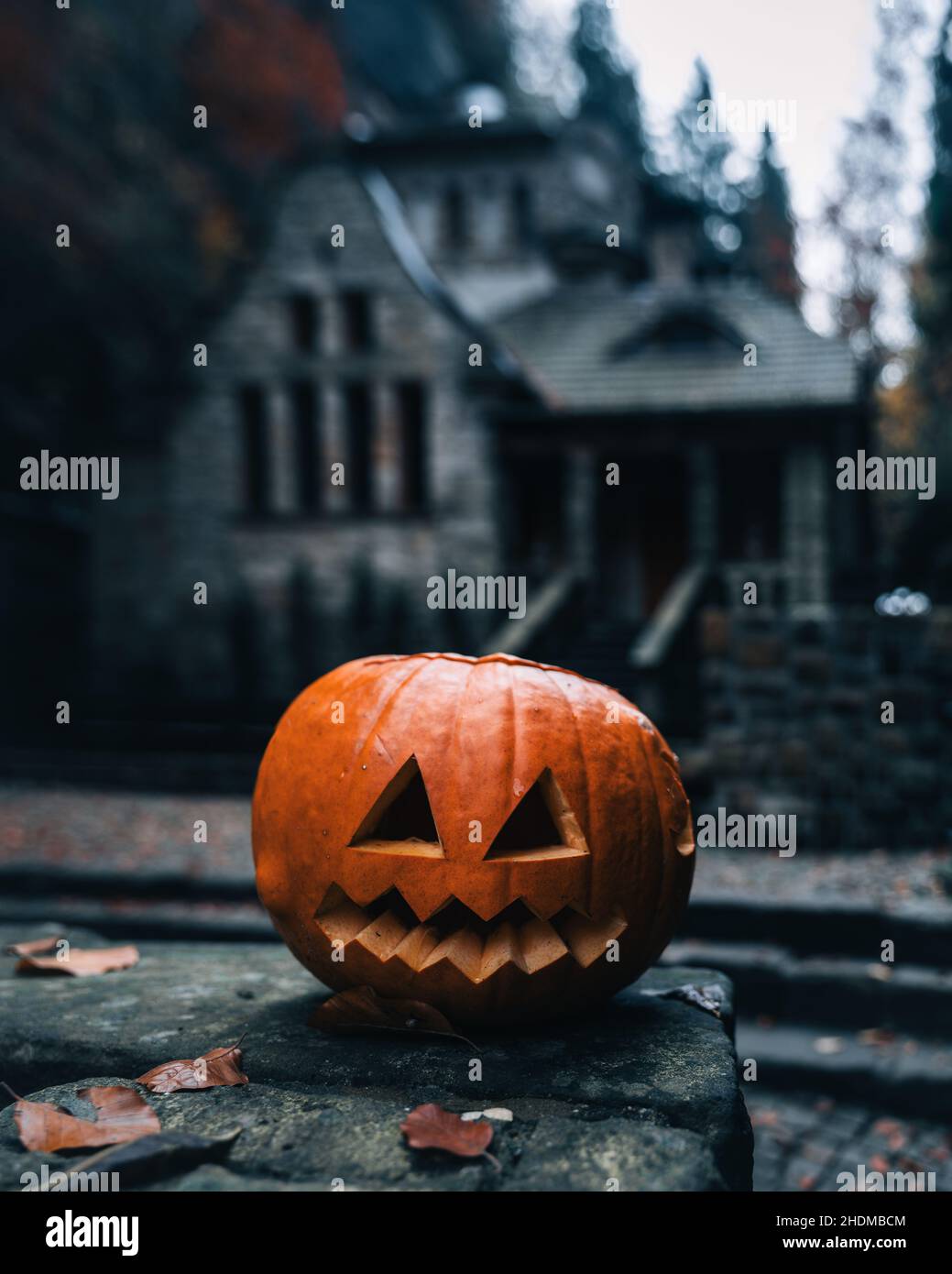 Vertical shot of a jack-o-lantern against a spooky house - Halloween ...