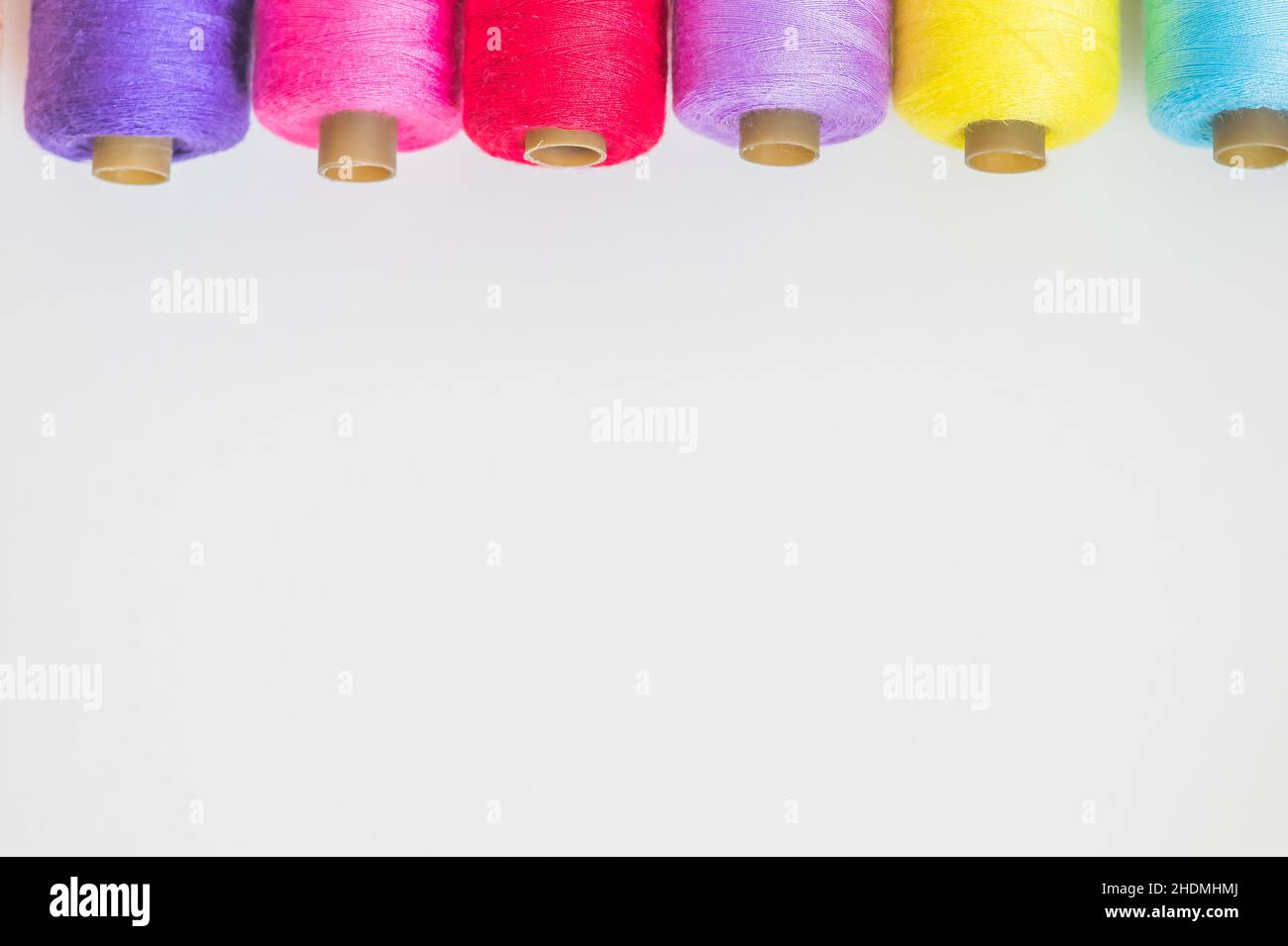 Colorful thread spools on a white background with copy space for text ...