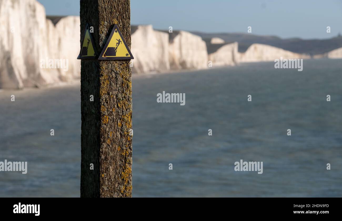 Yellow and black sign warning of the danger of erosion at the cliff ...