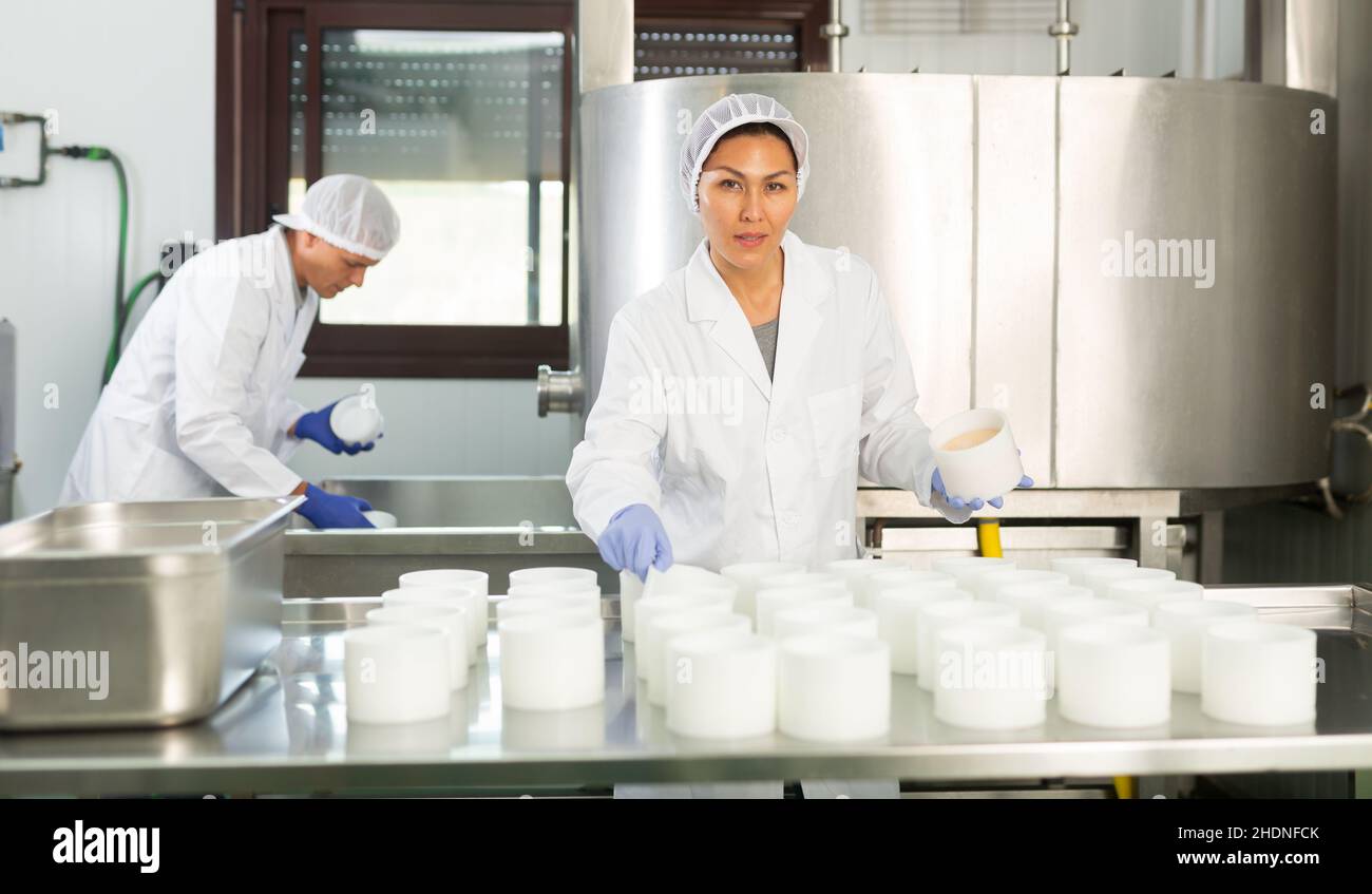 Woman wearing uniform showing cottage cheese production process on ...