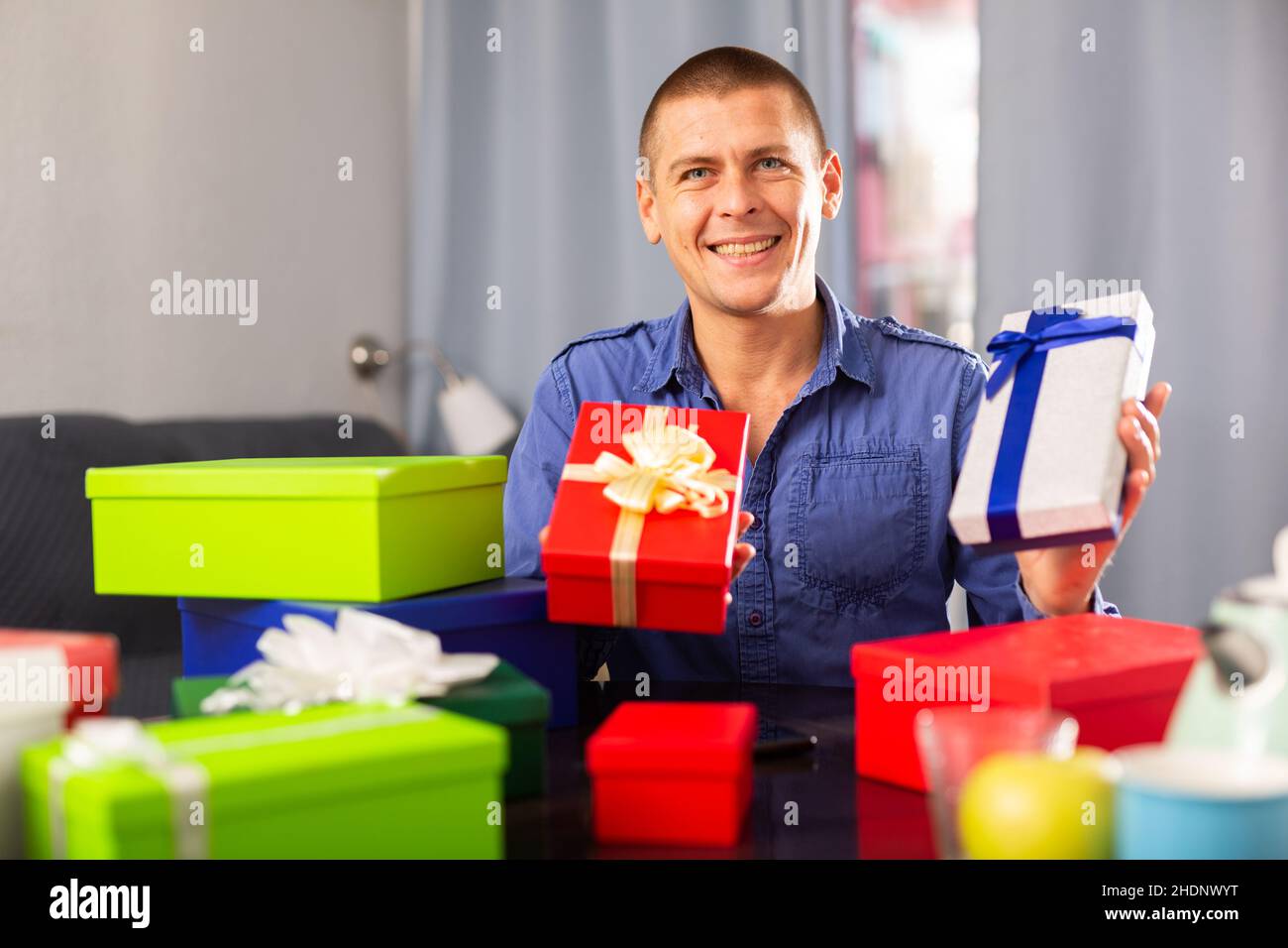 Man sitting with many presents in colorful boxes Stock Photo - Alamy