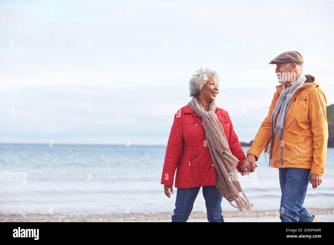 Senior couple walk hand in hand into the sea hi-res stock photography ...