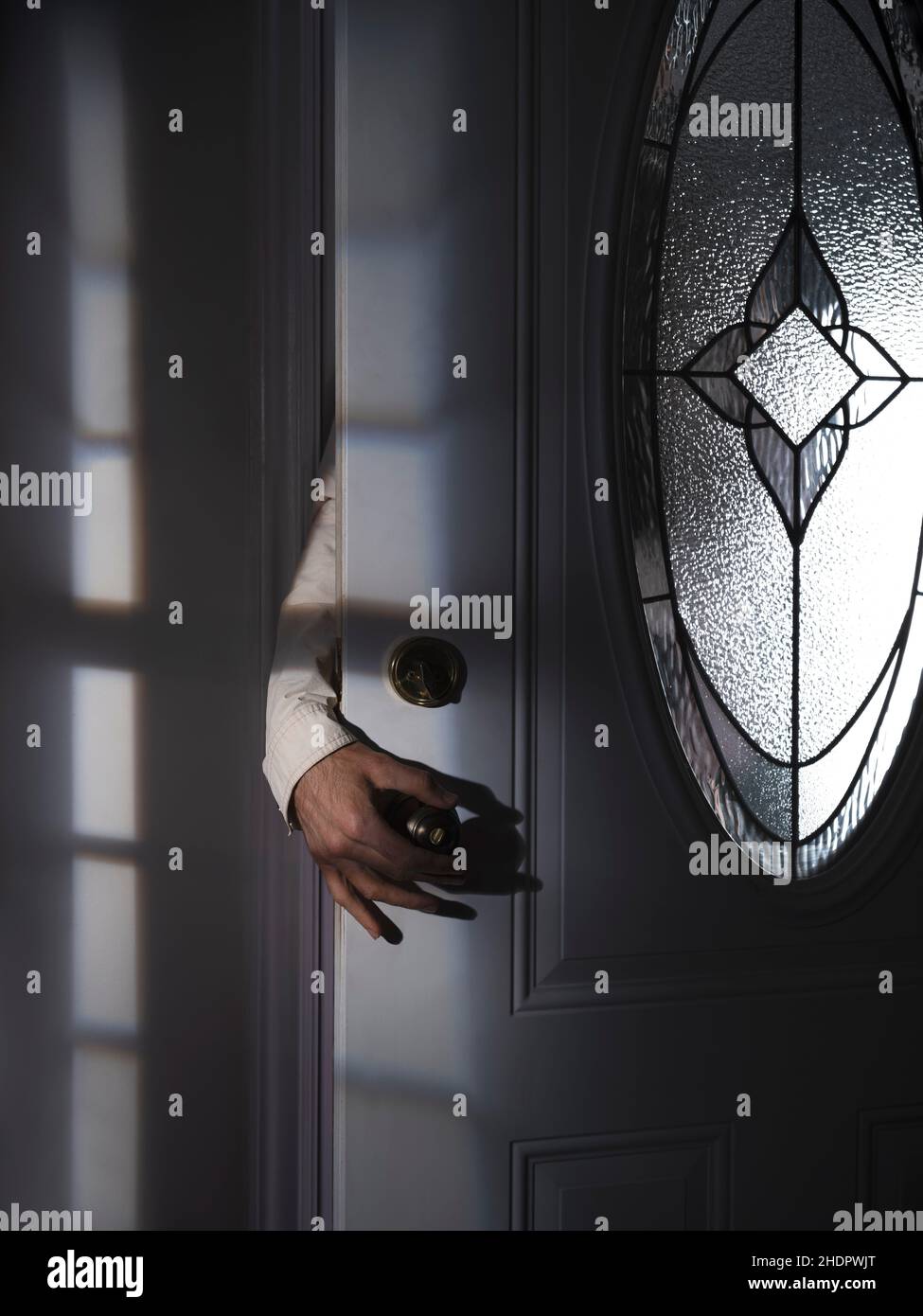 Man's hand reaching for a door handle from behind a slightly open ...