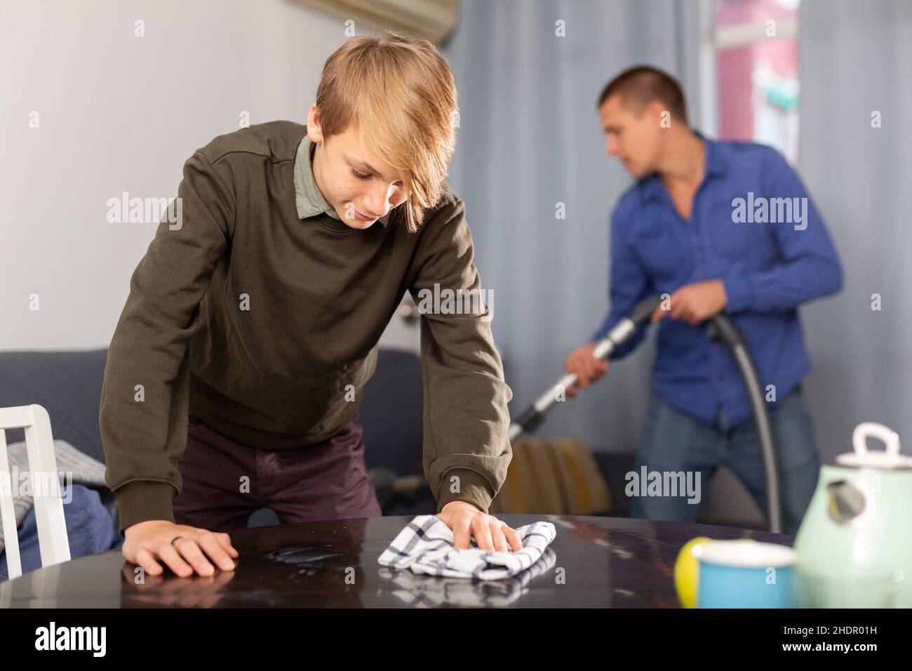 Teenager boy wiping dust from table Stock Photo - Alamy
