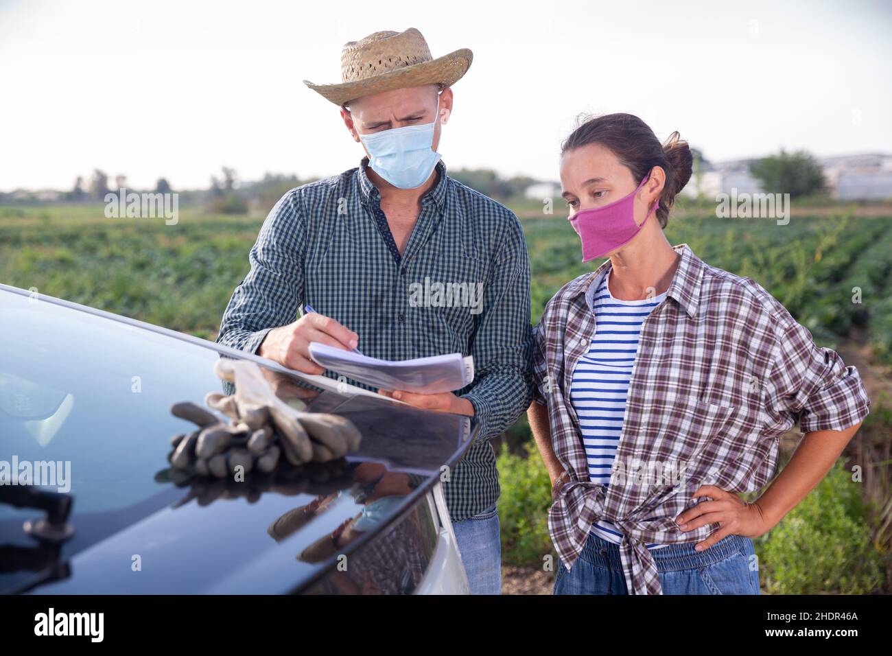 Hired worker in protective mask signs job application from farm owner ...