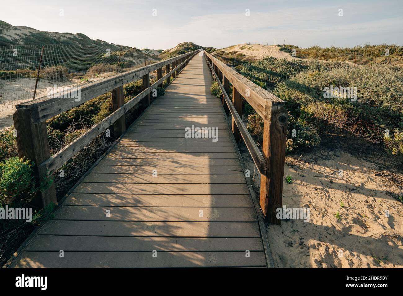 Rustic wooden beach boardwalk through sand dunes leading to the beach ...
