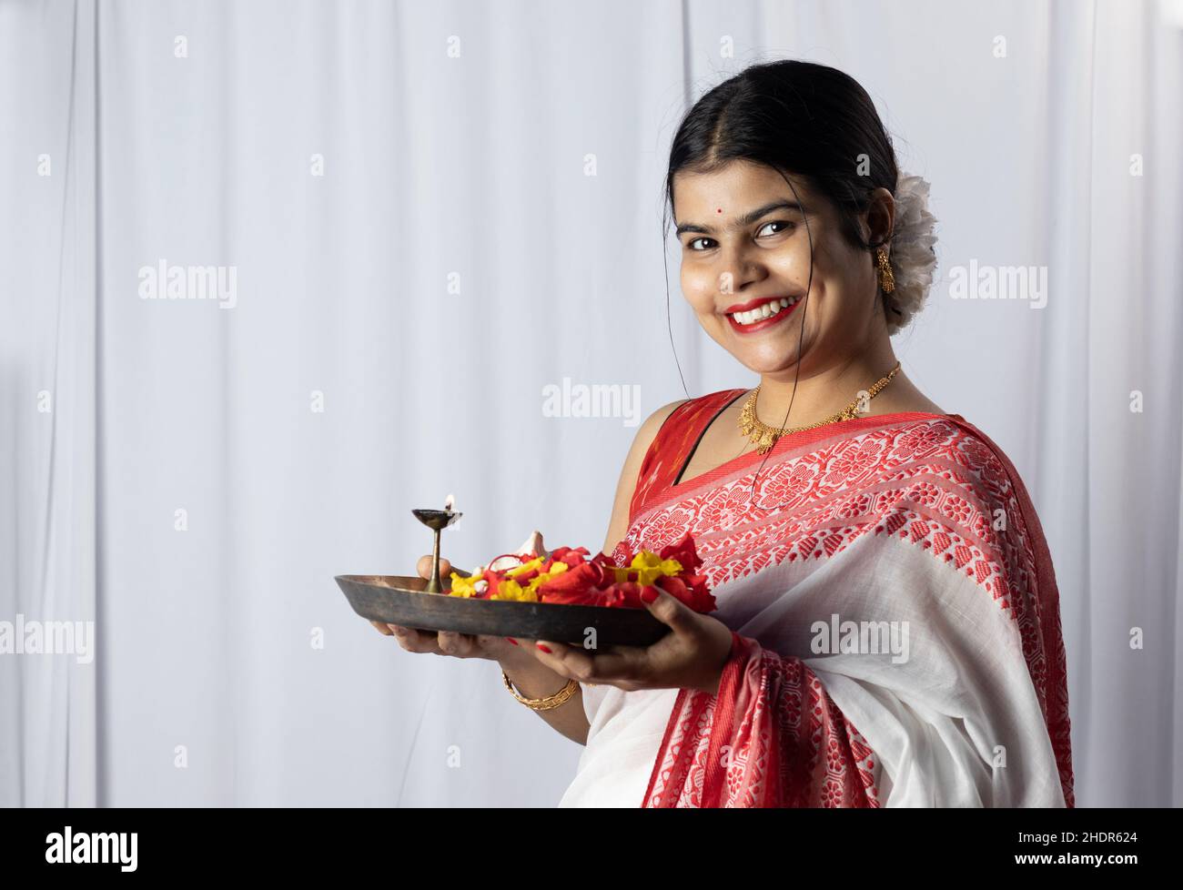A beautiful Indian woman in red saree holding puja thali or prayer ...