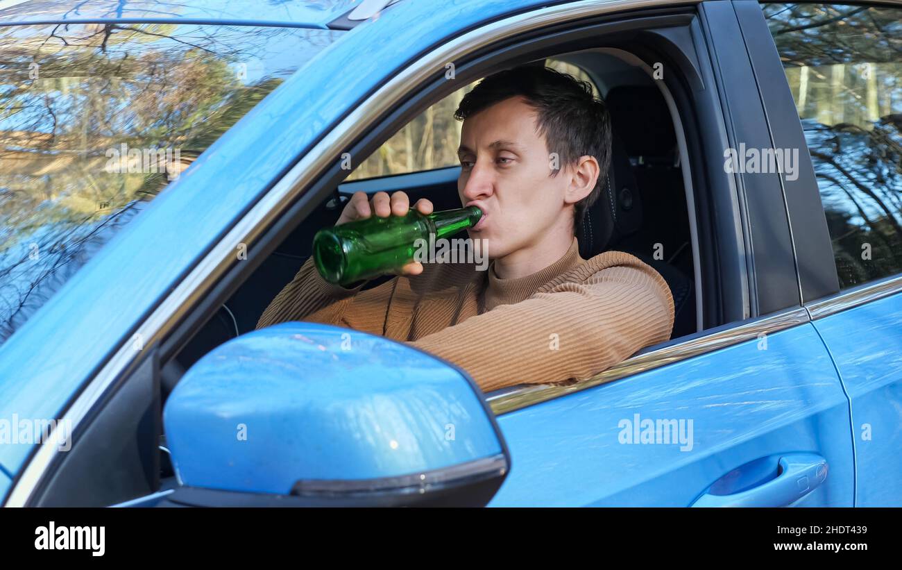 Driver drinks alcohol from bottle in car cabin after work Stock Photo ...