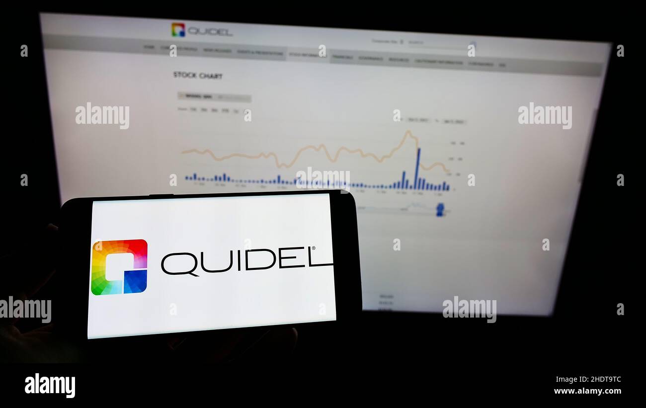 Person holding mobile phone with logo of US diagnostics company Quidel ...