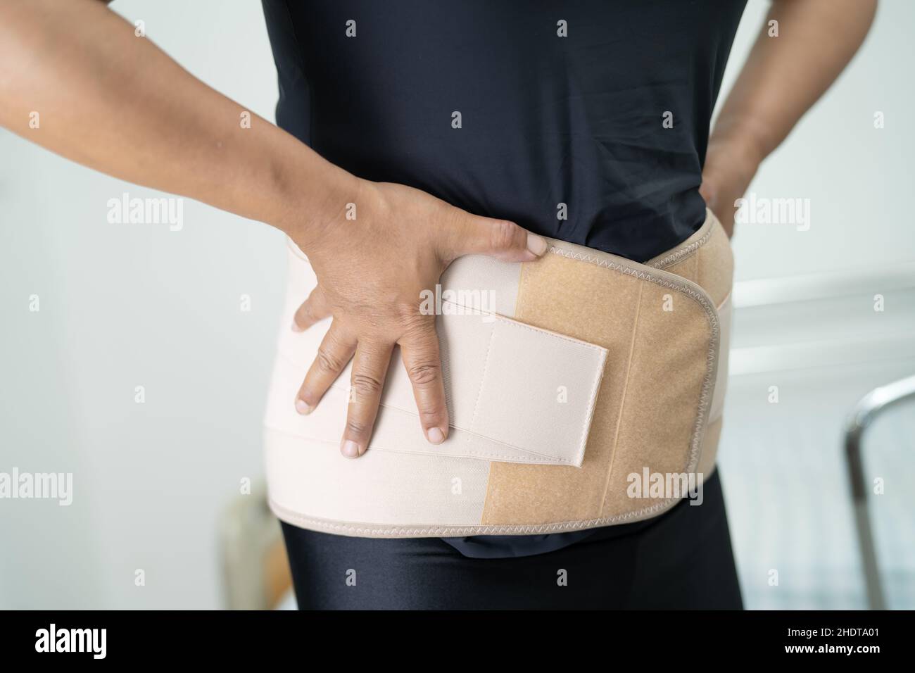Asian lady patient wearing back pain support belt for orthopedic lumbar ...