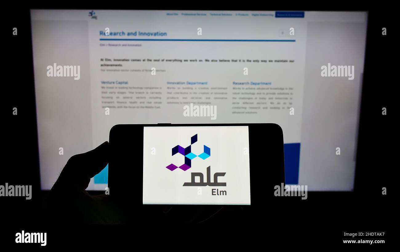 Person holding cellphone with logo of Saudi Arabian business Elm ...