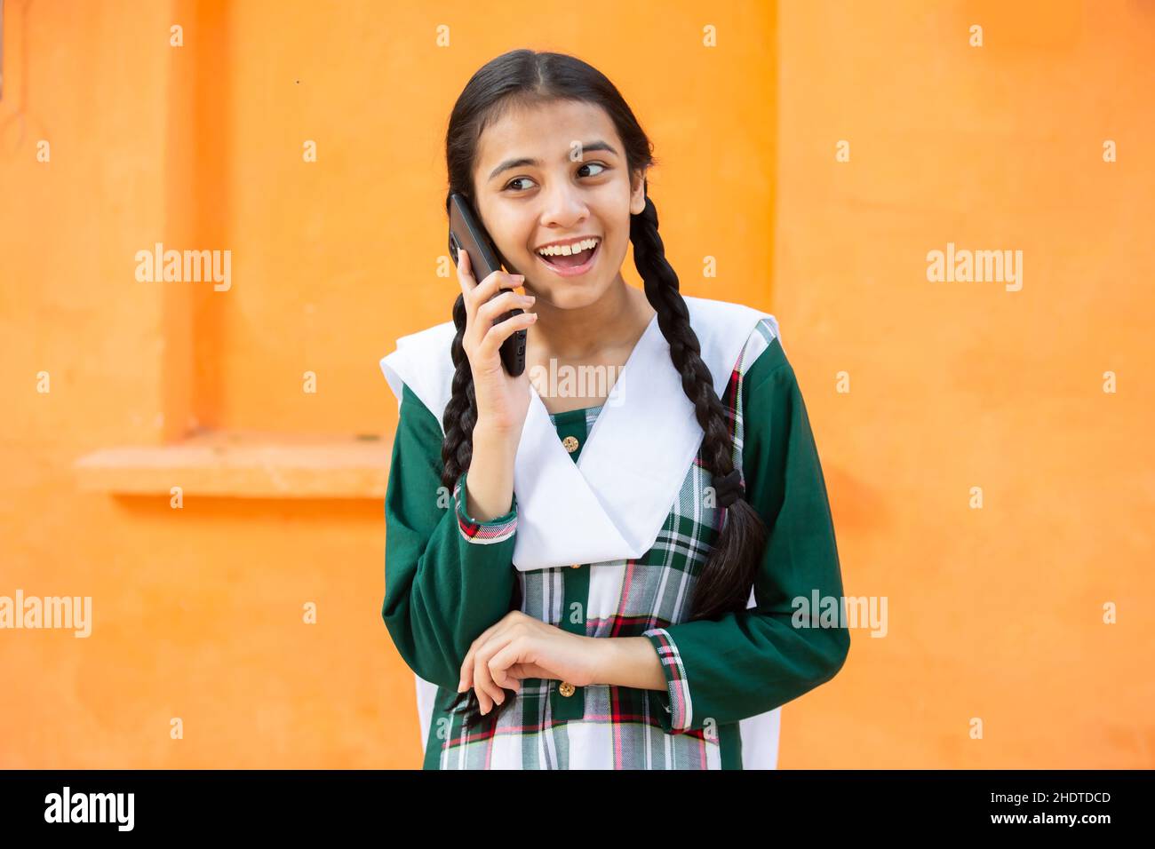 Young Happy Excited Indian Girl Talking On Smart phone against orange ...