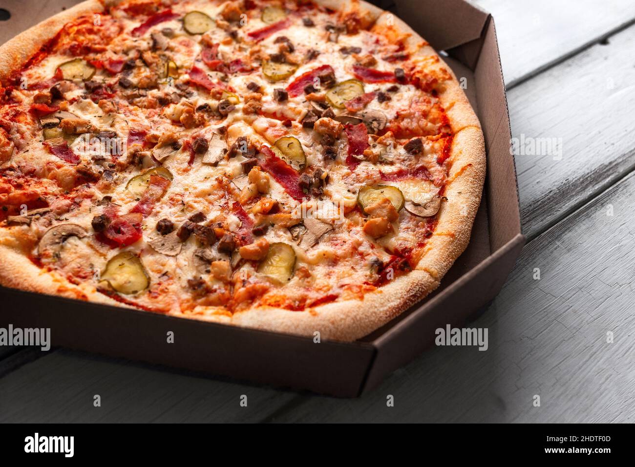 Pizza in a cardboard box with a variety of fillings close-up. Italian ...