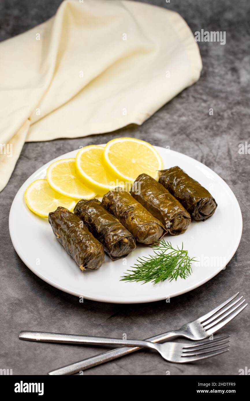 Stuffed grape leaves with olive oil on a dark background. Traditional ...