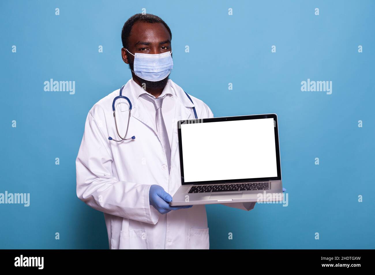 Doctor wearing medical protective gear presenting laptop with white ...