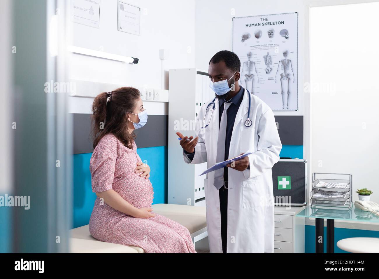 Doctor showing checkup files to pregnant woman in medical cabinet ...