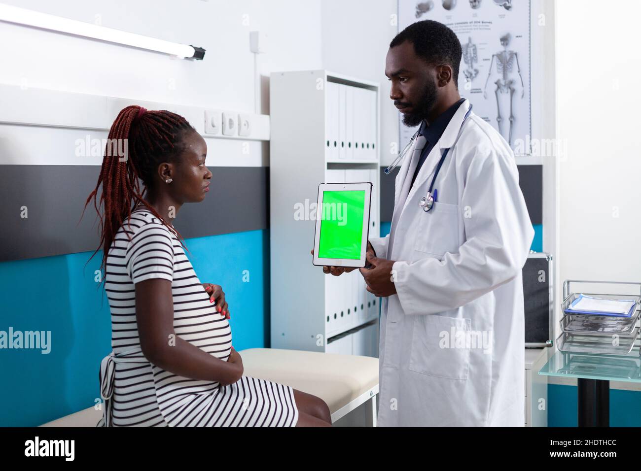 Doctor showing tablet with vertical green screen to pregnant woman ...