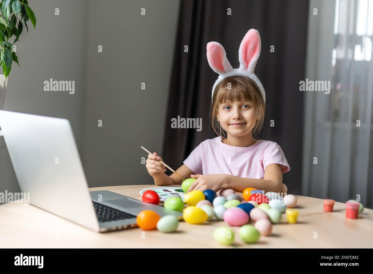 Little girl with her bunny using computer together preparing for easter ...