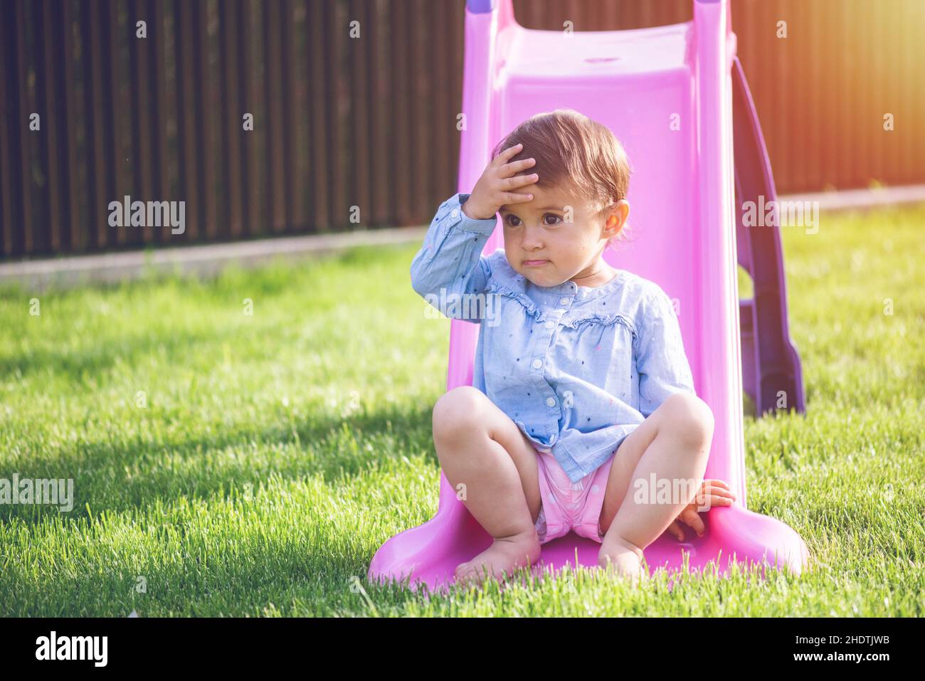 Little and cute girl play on slide and make a grimace while she play ...
