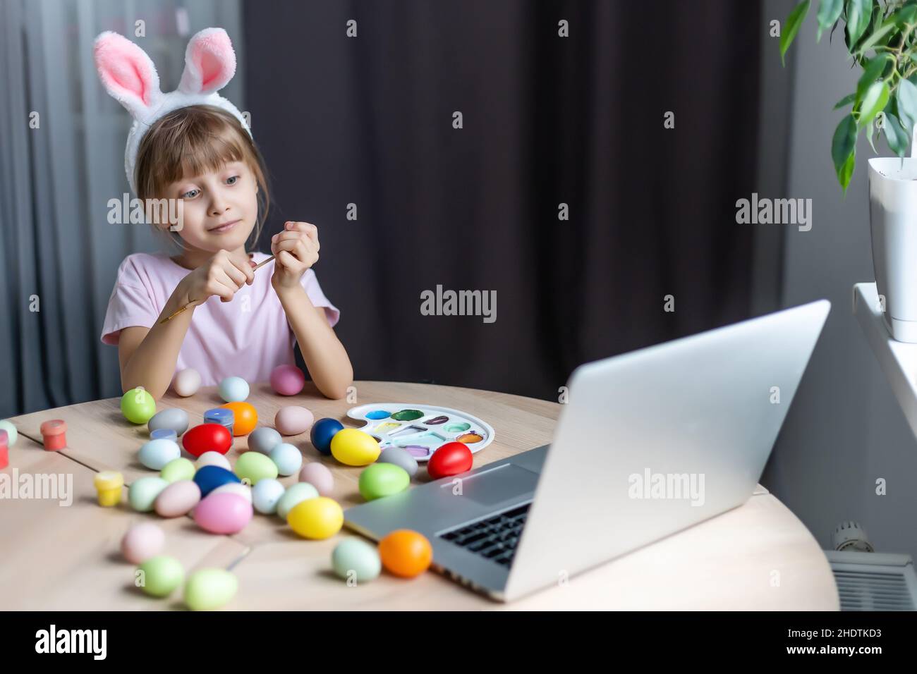 Little girl with her bunny using computer together preparing for easter ...