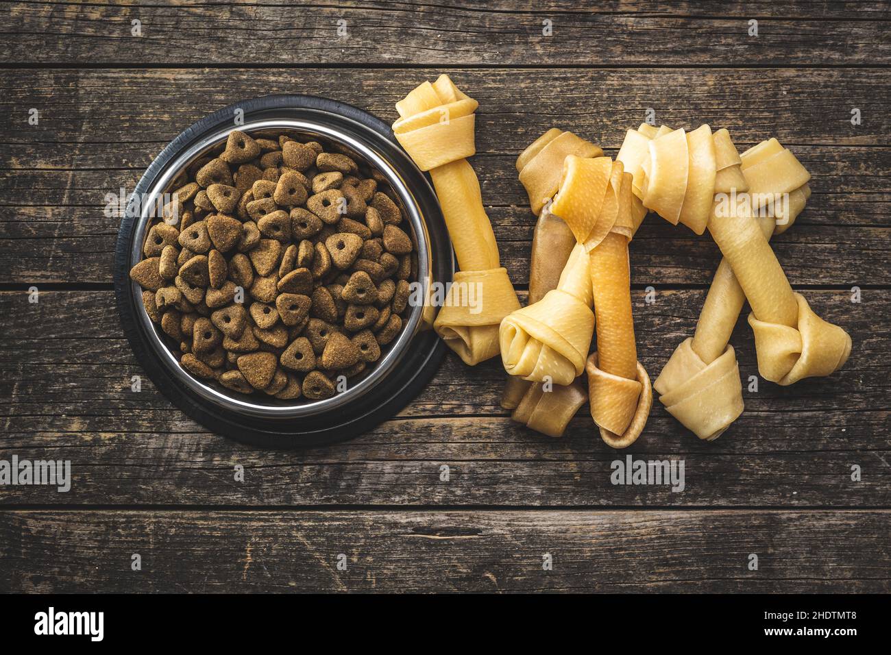 Delicacy for dogs. Chewing bone and dried food for dog on wooden table ...
