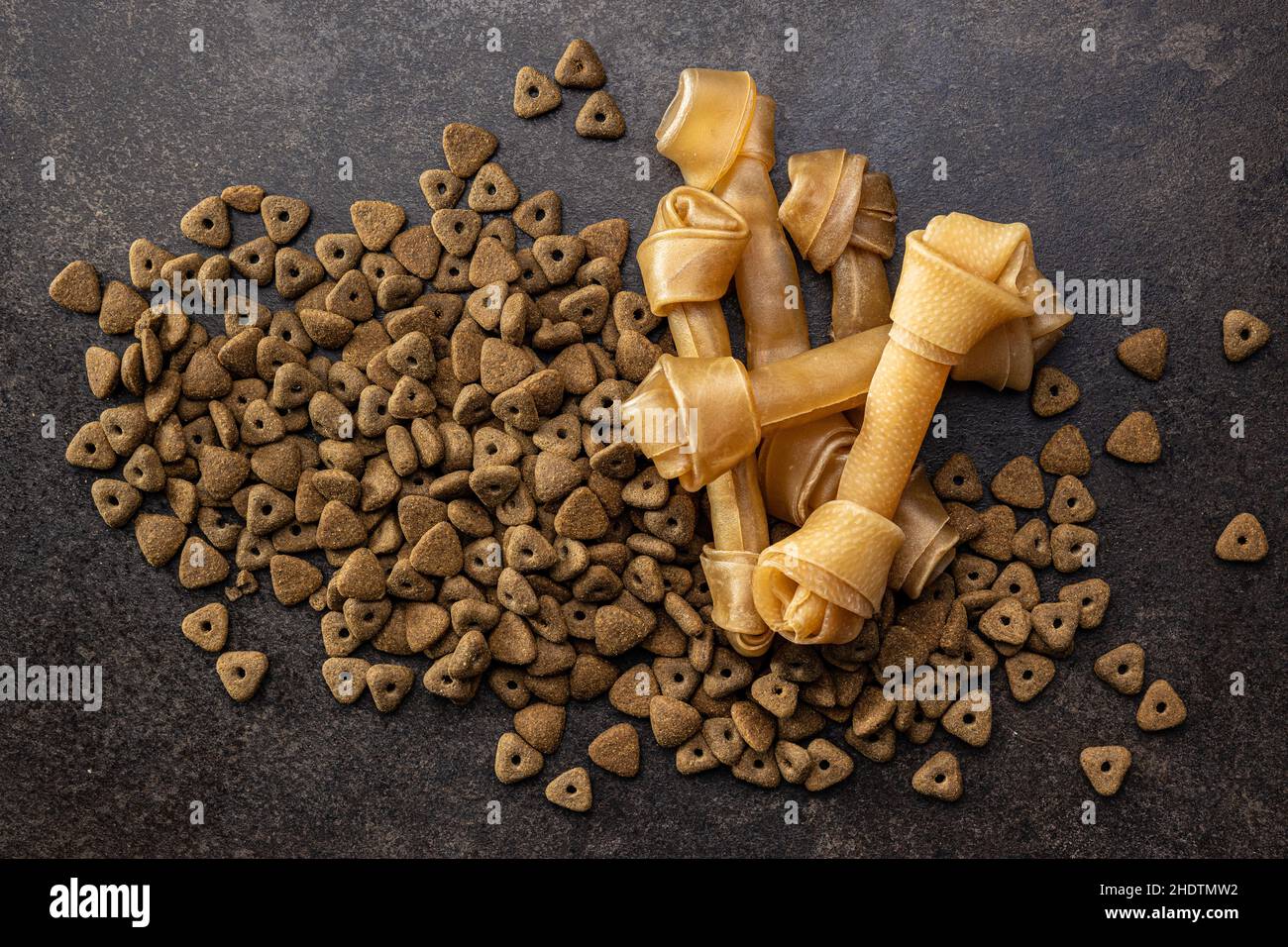 Delicacy for dogs. Chewing bone and dried food for dog on black table ...