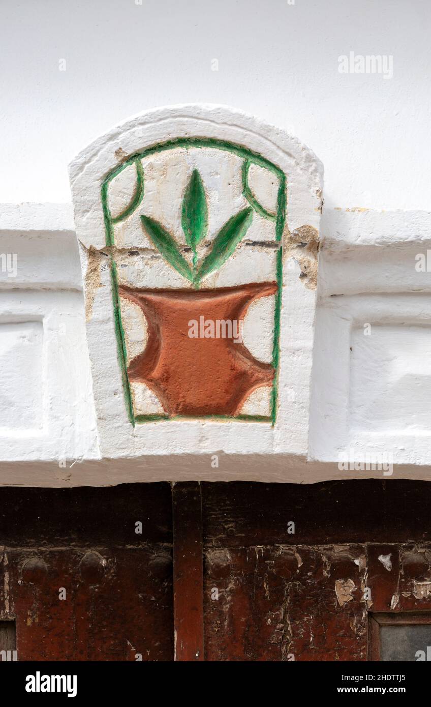 Architectural detail of clay plot and plant above doorway of house ...