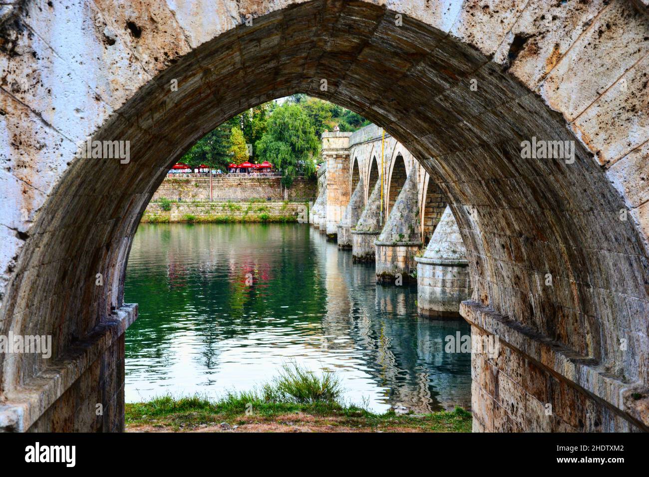 View of the river behind the arch of the stone bridge Stock Photo - Alamy