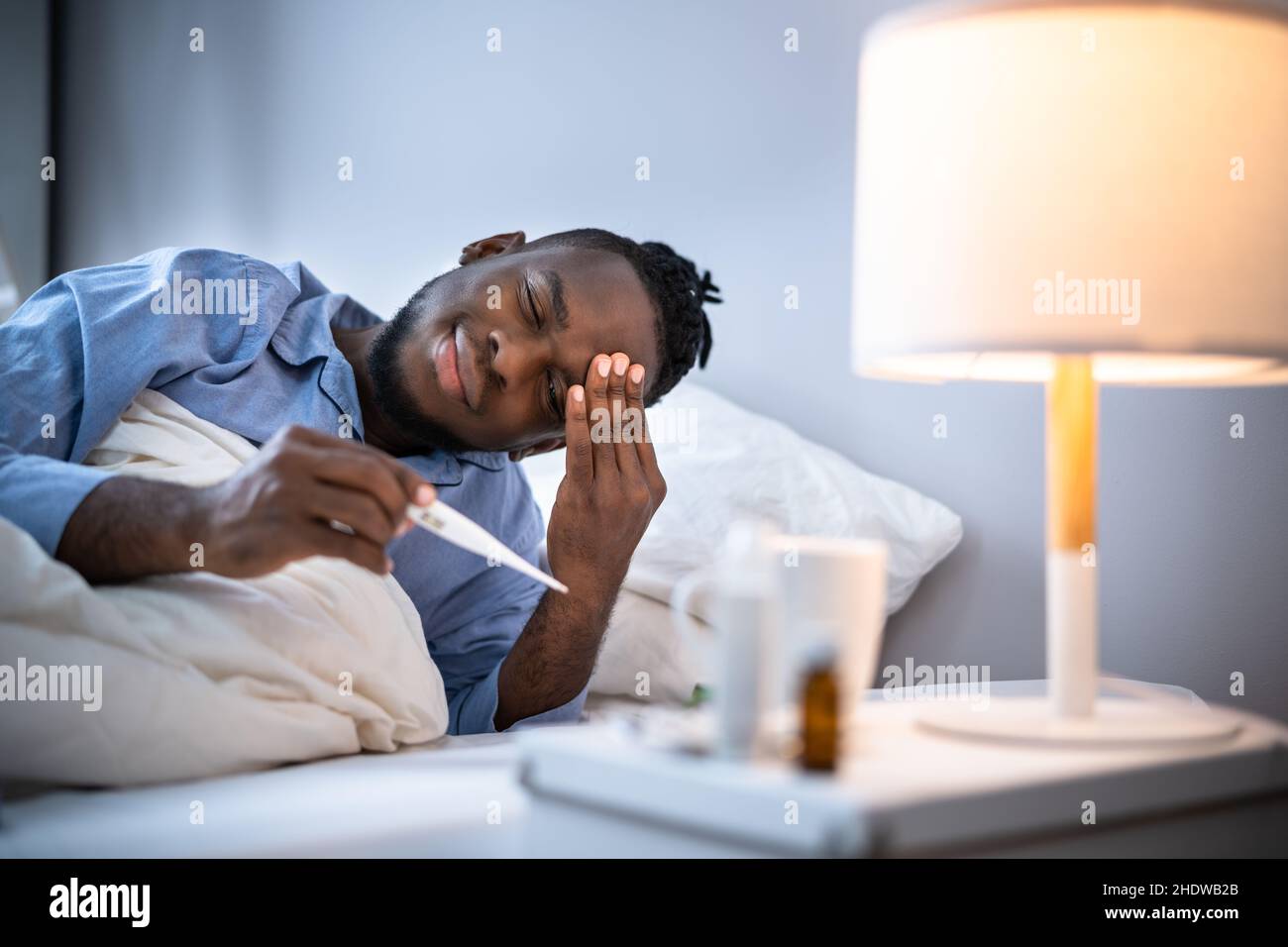 Sick Man With Fever Using Thermometer In Bed Stock Photo - Alamy