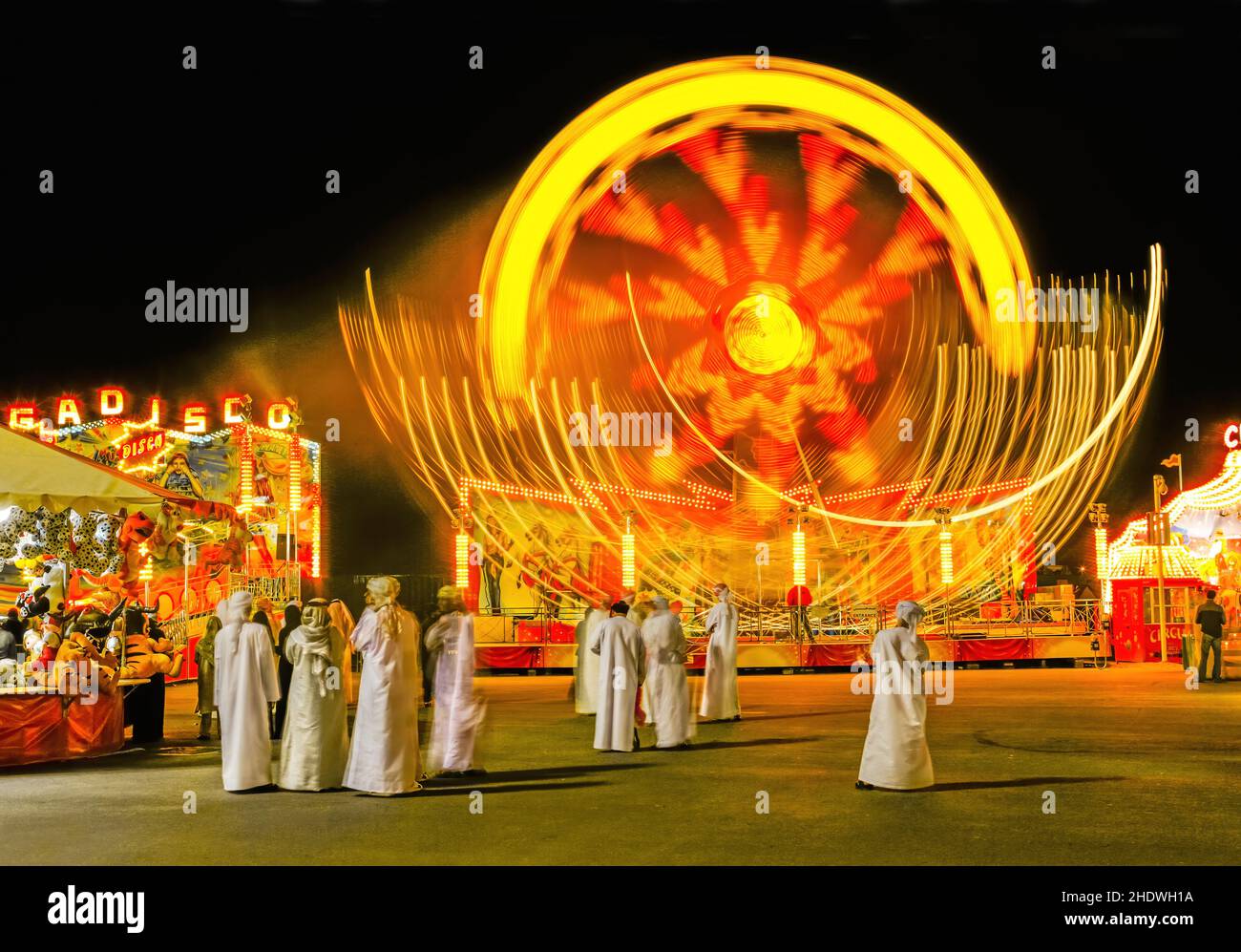 Unidentified Arab men watching a colourful ride at night at the fun ...