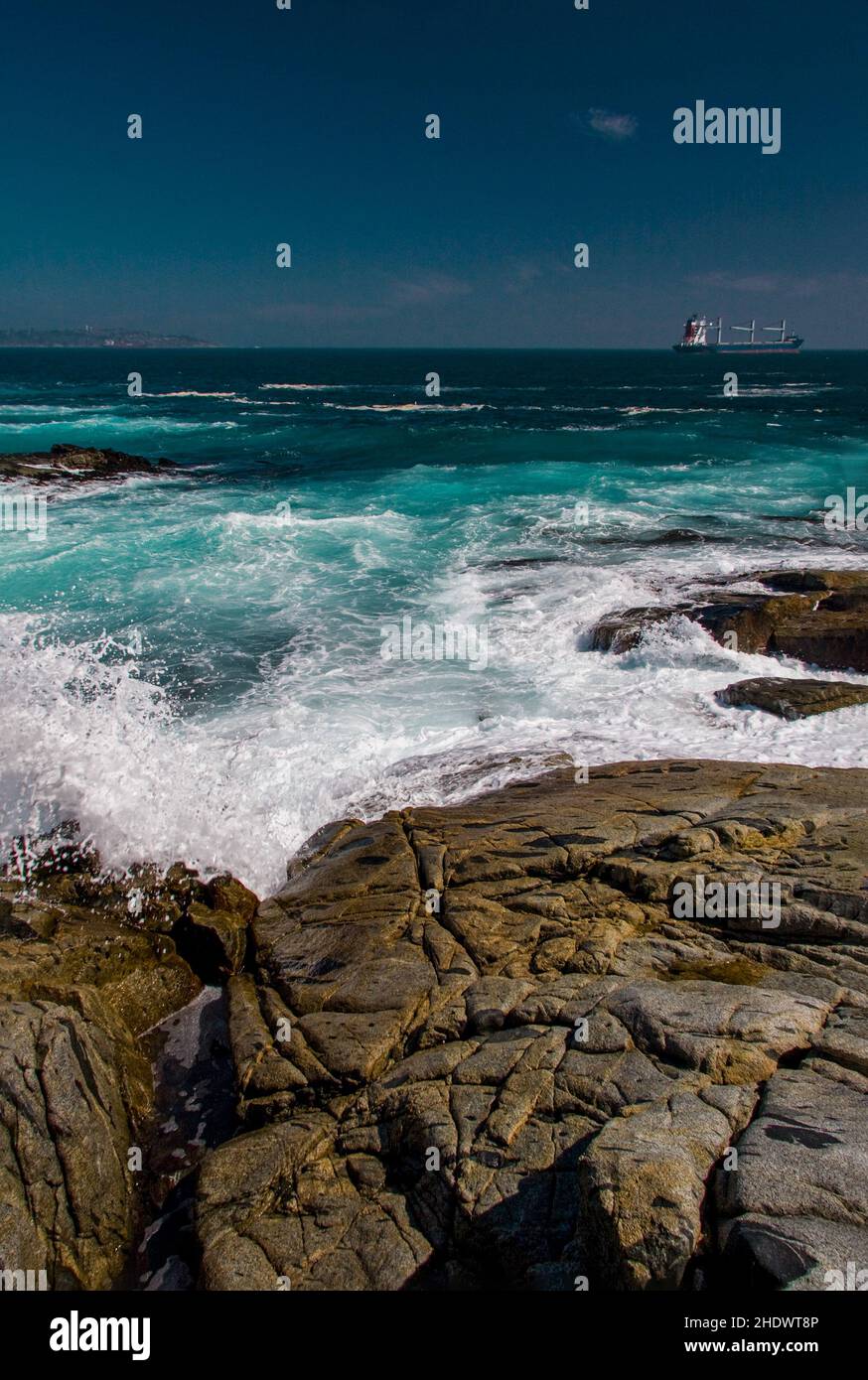 Vertical of the ocean waves hitting the rocks with a background of a ...