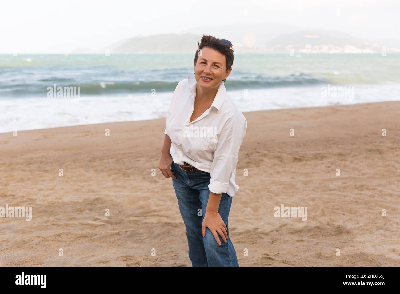 Portrait of a mature woman walking on the beach looking at the sea ...