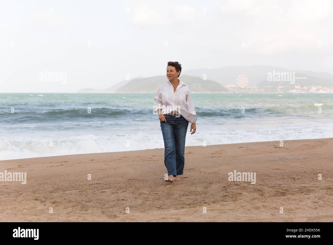Portrait of a mature woman walking on the beach looking at the sea ...