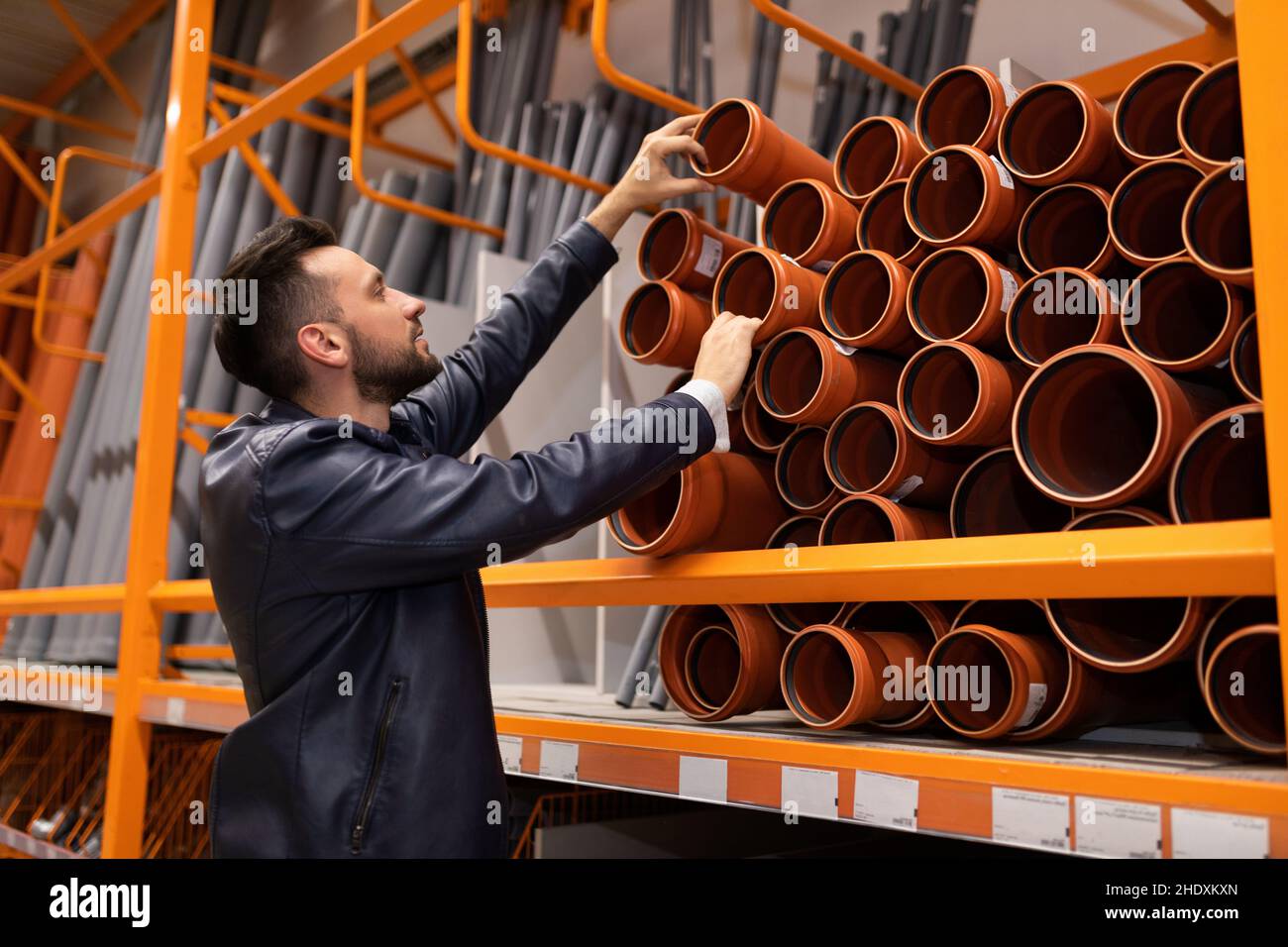 male plumber in a hardware store chooses the sewer pipes, the concept ...